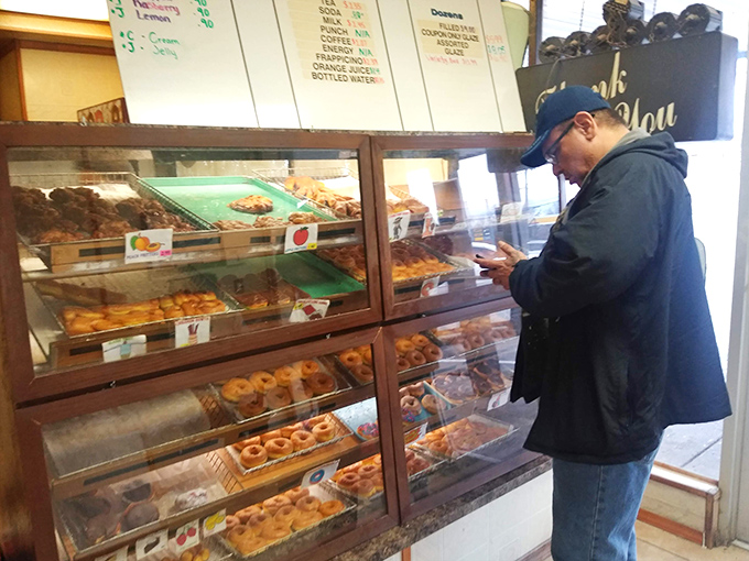 Decisions, decisions! Watching a fellow donut enthusiast choose their prize is like witnessing a kid in a candy store.
