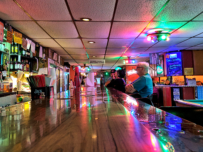 The bar at Alpine Inn&mdash;where strangers become friends over cold beers and chicken stories under the glow of colorful lights.