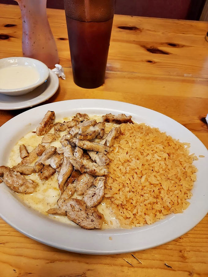 Tender slices of grilled chicken nestled on a bed of golden rice—a simple yet satisfying plate that proves sometimes the most straightforward dishes carry the most flavor.