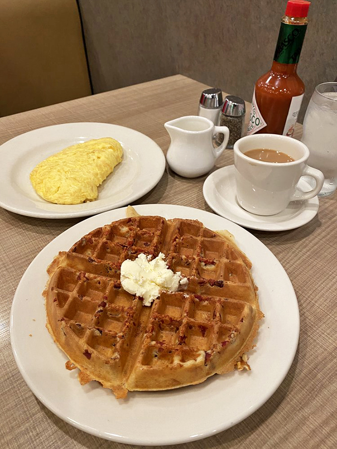 A perfect breakfast trinity: golden waffle with a dollop of butter, fluffy omelette, and coffee that promises to jumpstart your day.