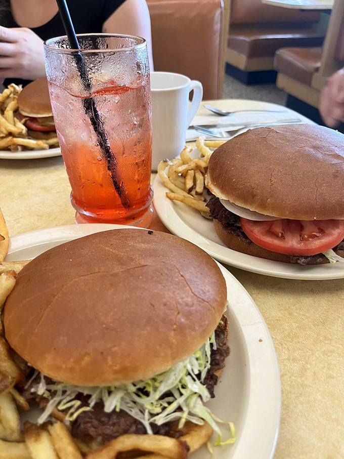 The holy trinity of diner perfection: two perfectly executed burgers, golden fries, and a cherry drink that somehow makes everything taste even better.