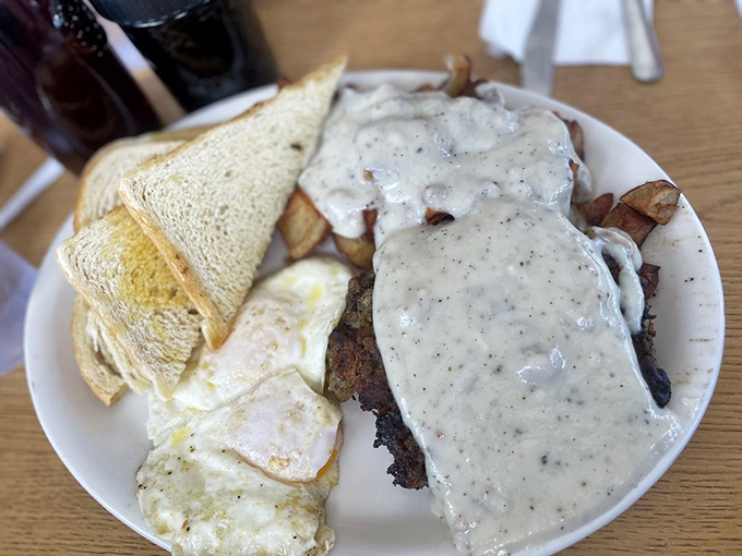 Chicken fried steak smothered in country gravy—comfort food that hugs your soul while simultaneously plotting against your arteries.