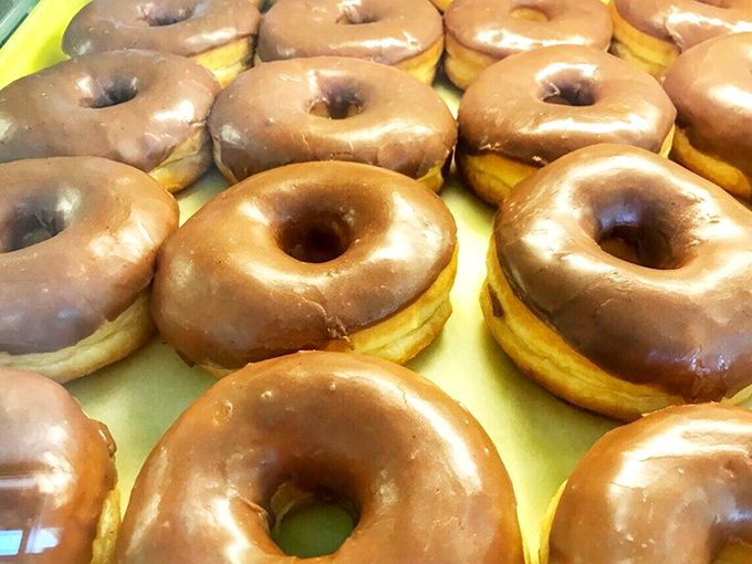 Chocolate-glazed donuts lined up like sweet soldiers. One bite through that glossy exterior reveals heavenly softness beneath.