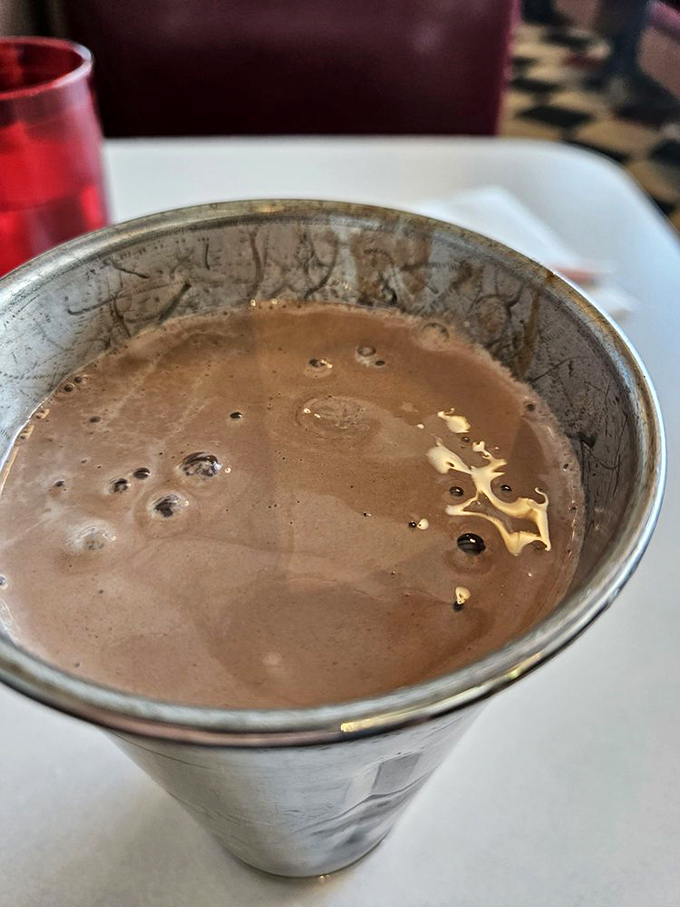 This isn't just a chocolate milkshake—it's a time machine in a metal cup, thick enough to require serious straw commitment and patience worthy of the reward.