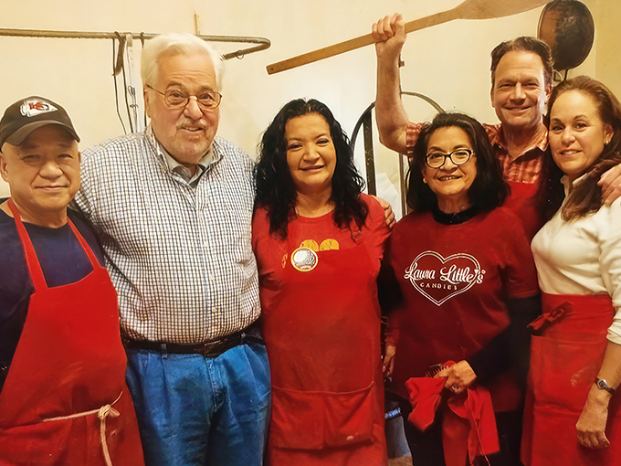 The passionate team behind the sweetness, wooden spoon raised like a conductor's baton orchestrating the next symphony of chocolate delights.