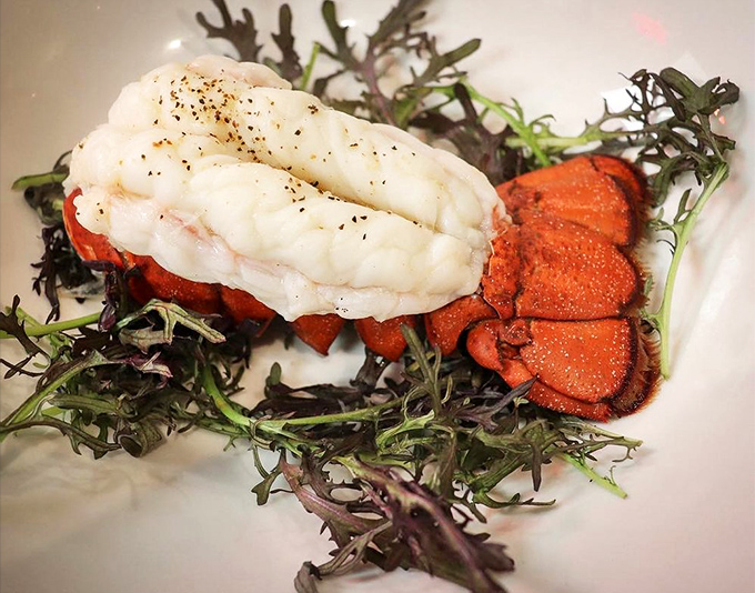 This lobster tail isn't just seafood; it's a coastal treasure resting on a bed of greens like Neptune's crown jewel.