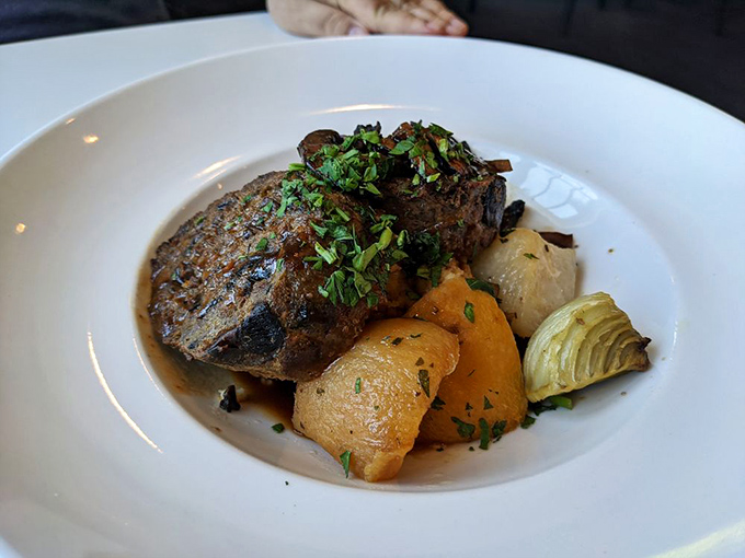 A perfectly seared steak rests in its savory jus alongside roasted vegetables &ndash; proof that simple ingredients handled with respect create extraordinary meals.