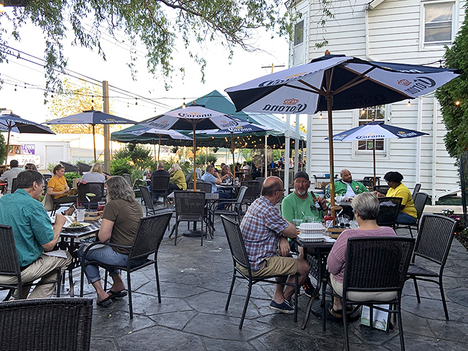 The outdoor patio at dusk, where string lights twinkle overhead and conversations flow as easily as the Northeast River nearby.