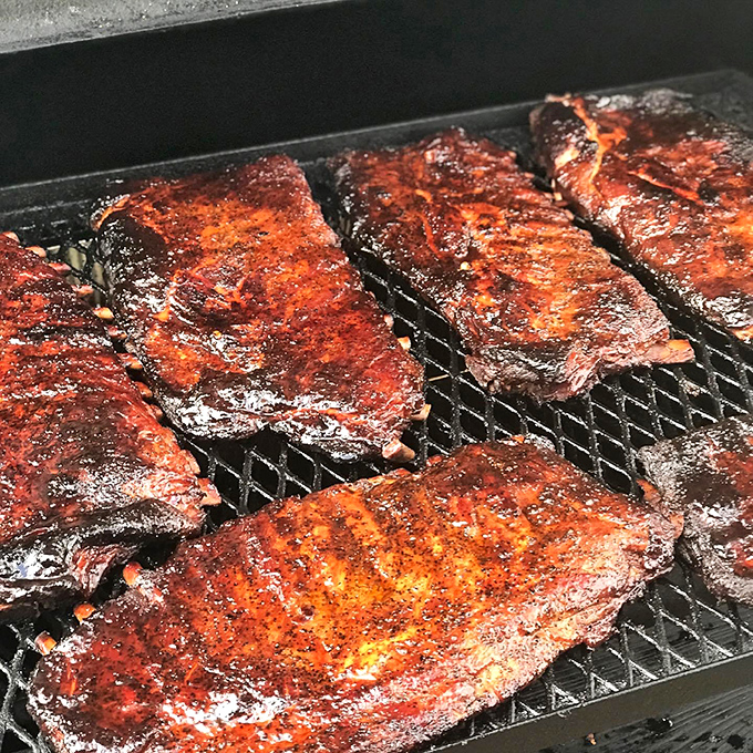 These ribs glisten in the smoker like rubies in a jewelry case. The bark has that perfect mahogany color that whispers, "I'm worth the wait."