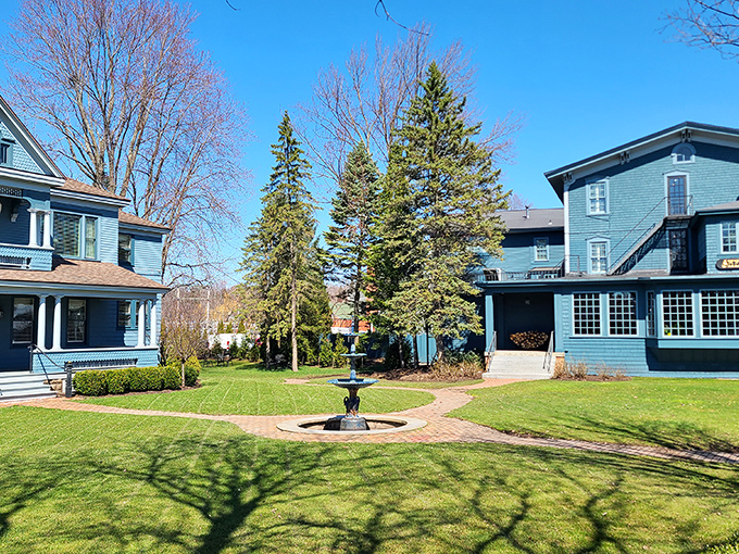 Blue Victorian buildings framing a courtyard fountain&mdash;Gilded Age elegance that whispers of afternoon tea and Sunday promenades. Downton Abbey meets upstate New York.