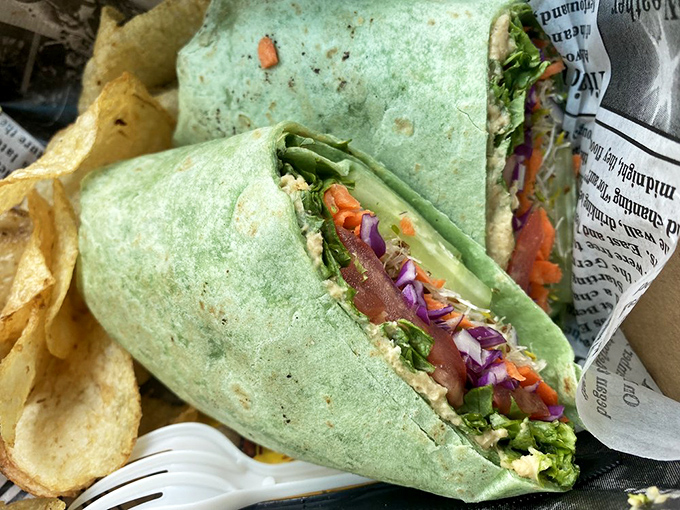 A vibrant green wrap bursting with fresh vegetables and crispy chips on the side&mdash;because even at 10,000 feet, healthy options deserve flair.