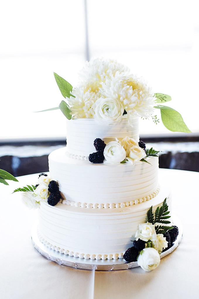 This wedding cake isn't just dessert&mdash;it's an architectural marvel of white frosting, fresh flowers, and blackberries that promises "happily ever after" with every tier.