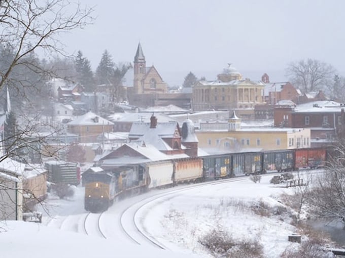 Winter blankets Oakland in pristine white, transforming the town into a snow globe scene where even passing trains look like they're delivering Christmas magic.