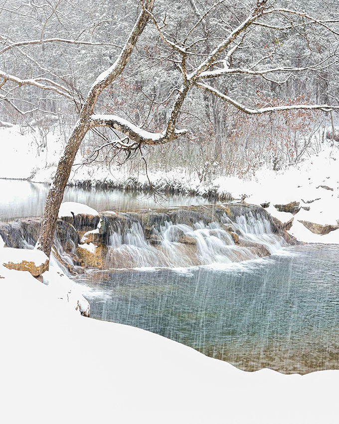 Even in winter's embrace, Chickasaw National Recreation Area's waterfalls refuse to sleep, flowing beneath a delicate blanket of snow in ethereal silence.