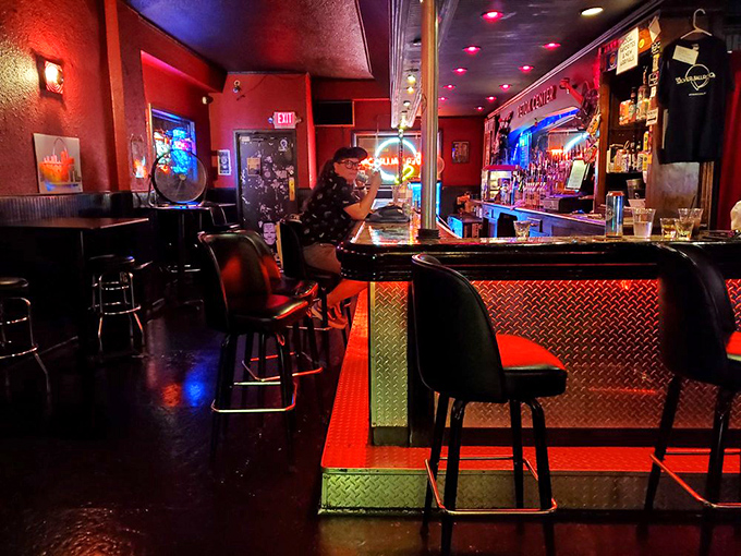 The diamond-plate bar front gleams under red lighting, creating the perfect perch for between-game refreshments and pinball strategy sessions.