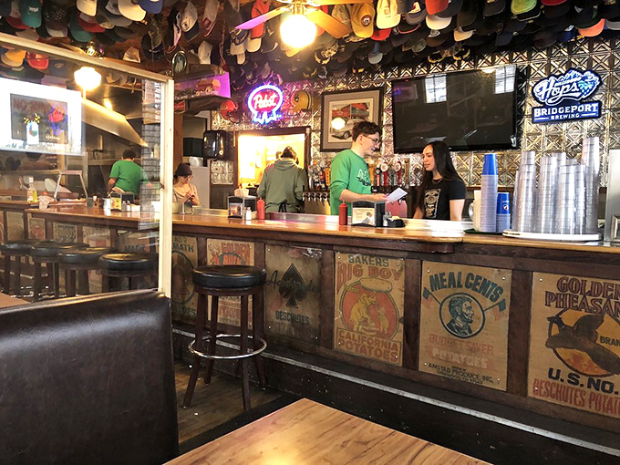The bar where magic happens—vintage signs and friendly faces create the perfect backdrop for burger anticipation.