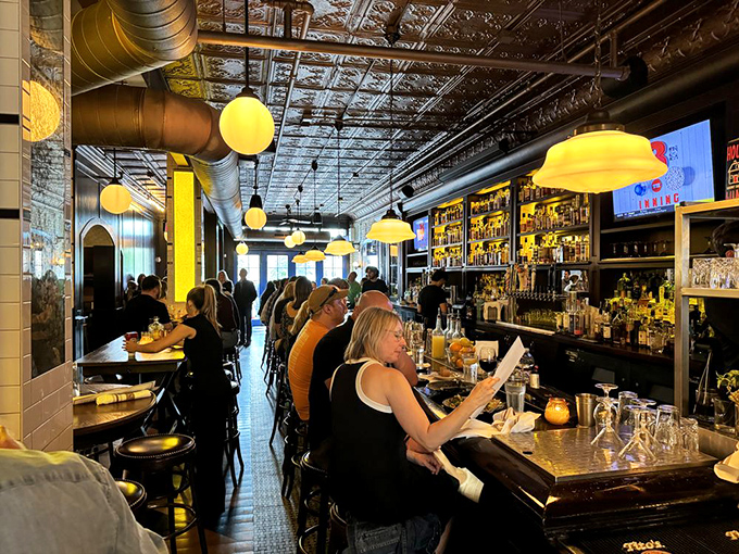 A bar where strangers become neighbors. The backlit bottles create a whiskey library where everyone's card is valid.