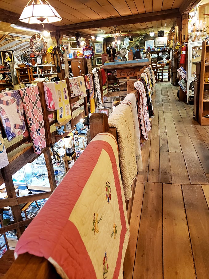 Handmade quilts draped like colorful flags, each stitch representing hours of craftsmanship that HGTV could never replicate.