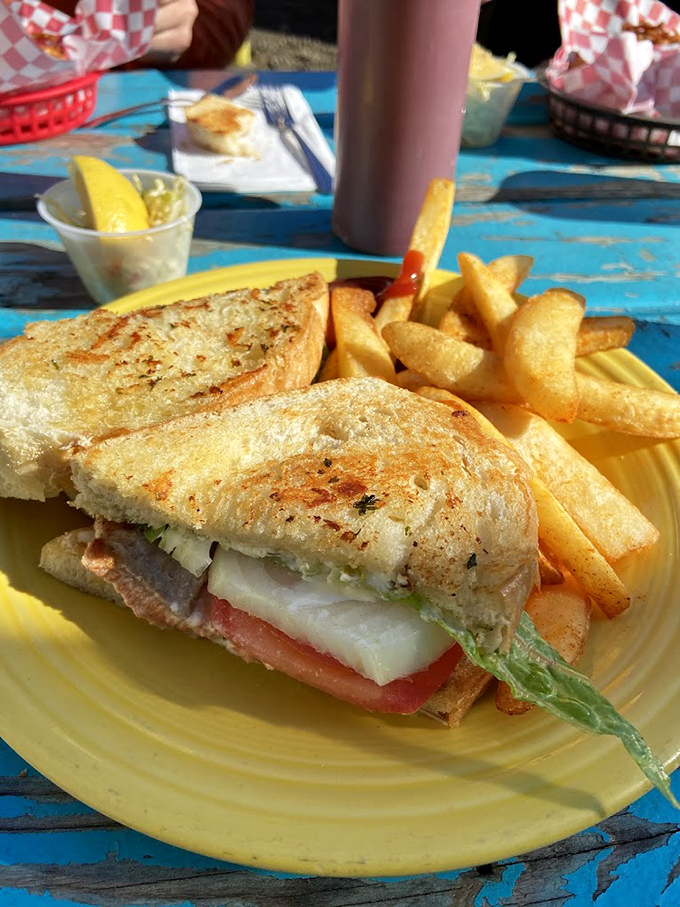 A sandwich that doesn't need to shout for attention—just perfectly grilled bread embracing fresh seafood with a side of hand-cut fries.