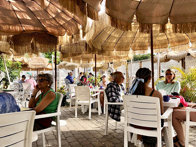 The outdoor seating area offers a tropical oasis under thatched umbrellas—breakfast with a side of vacation vibes.