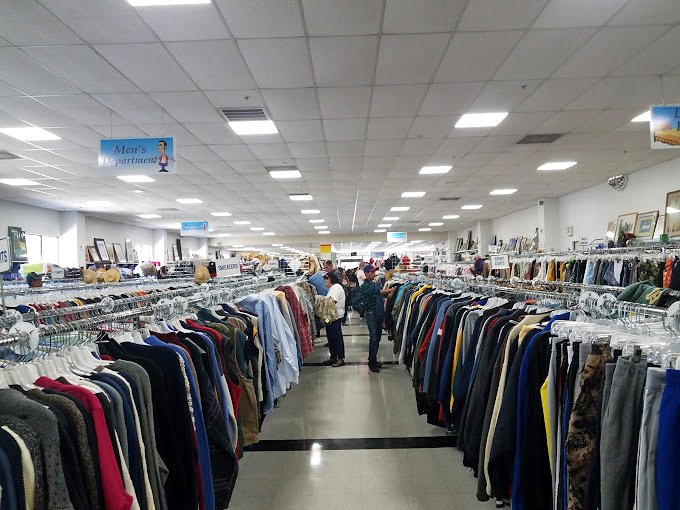 Serious thrifters scan the aisles with practiced eyes. The gentleman checking that jacket knows quality stitching when he sees it.