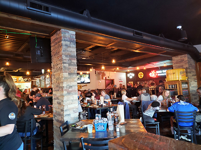 A packed house of happy diners under exposed ductwork and stone columns&mdash;proof that good barbecue builds community one platter at a time.