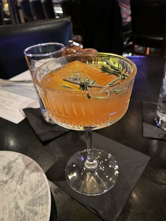 This isn't just a cocktail; it's a sunset in a glass with rosemary playing the role of beachside vegetation.