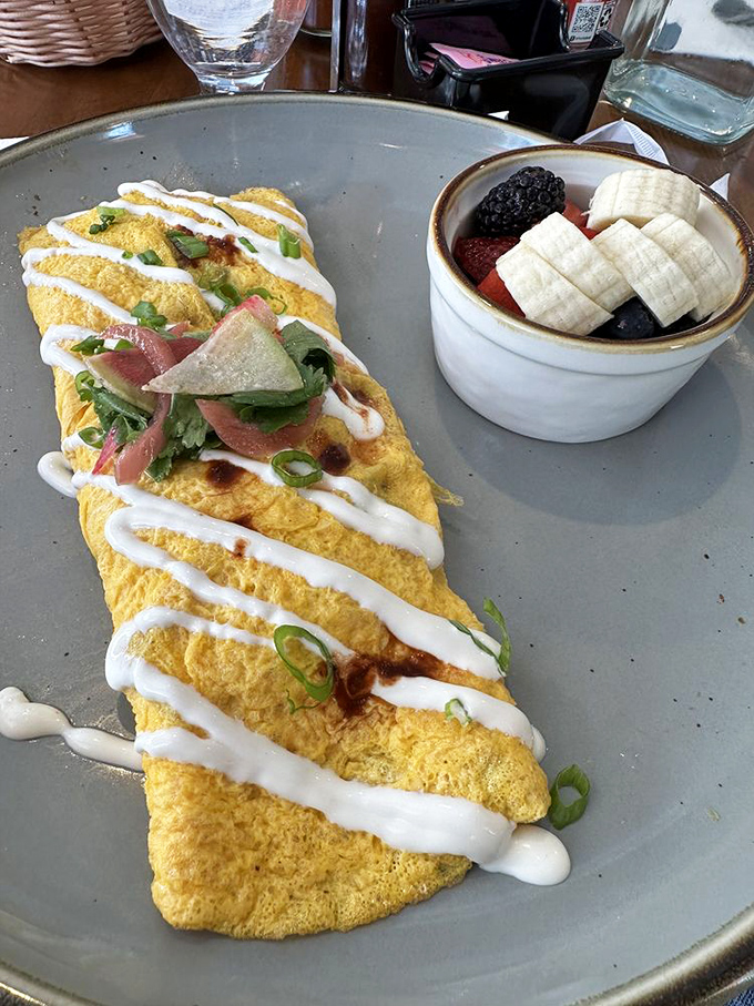 This omelet, draped in creamy sauce and garnished with fresh tomatoes, is what breakfast dreams are made of&mdash;fluffy, flavorful, and unapologetically indulgent.