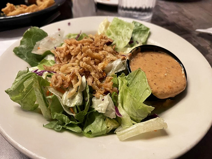 A simple house salad gets dressed up with crispy fried onions and a side of creamy dressing&mdash;proving even the greens get special treatment.