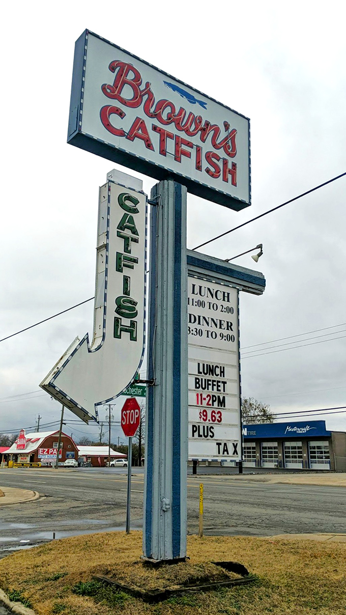 The roadside sign stands tall like a deep-fried North Star, guiding hungry travelers to the promised land of all-you-can-eat catfish.