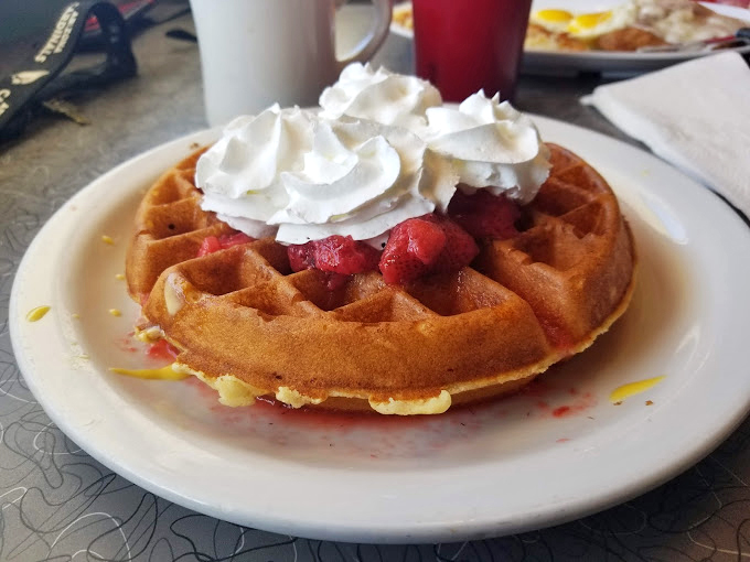 A waffle that understands the assignment &ndash; golden, crisp exterior giving way to fluffy interior, topped with strawberries and whipped cream. Breakfast or dessert? Yes.