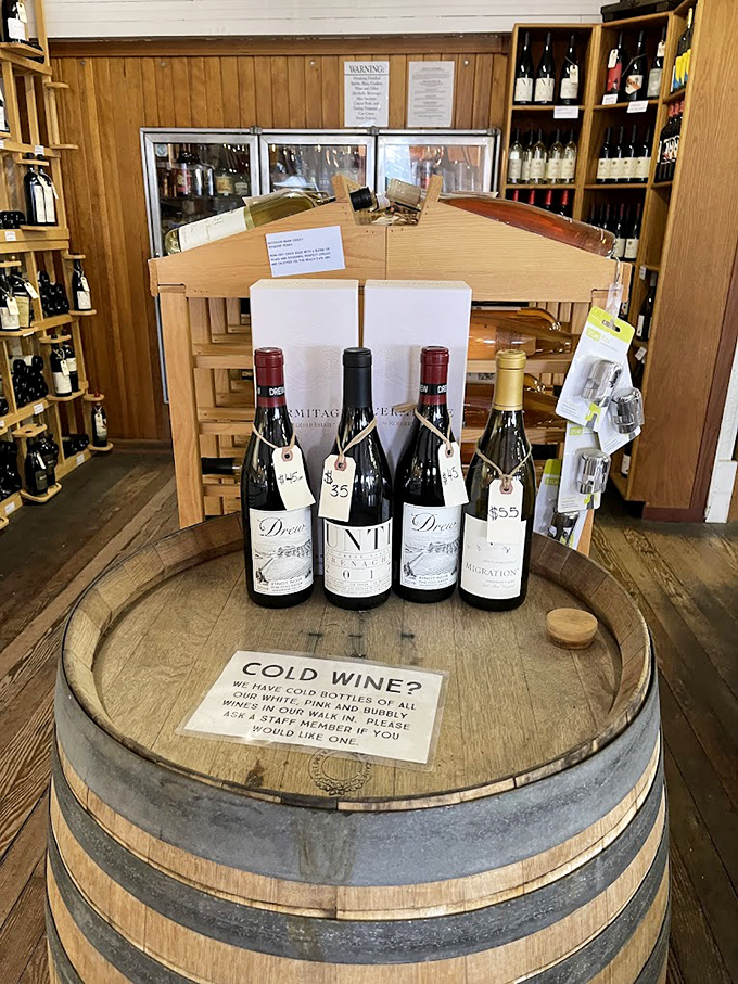 Wine bottles standing at attention on an oak barrel&mdash;California's liquid poetry waiting to accompany your sandwich masterpiece. The perfect road trip detour.