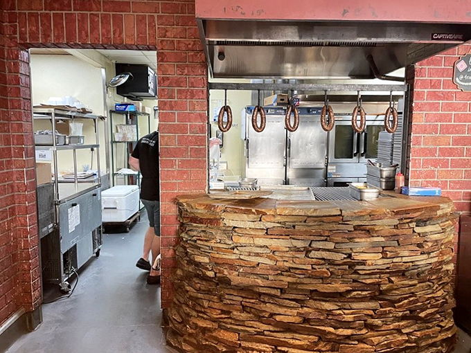 Behind the stone counter, barbecue magic happens in a kitchen where smoke and fire transform ordinary cuts into extraordinary meals.