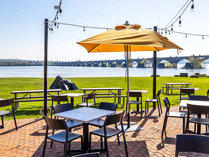 Outdoor dining with yellow umbrellas and string lights&mdash;where the Susquehanna River view comes complimentary with every order.