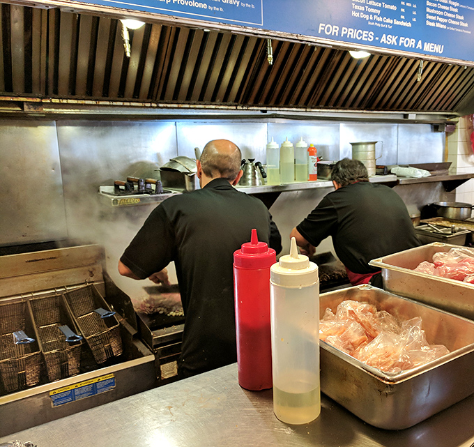 Behind the counter, sandwich artisans perform their daily magic. No capes needed when you wield spatulas with this much authority.