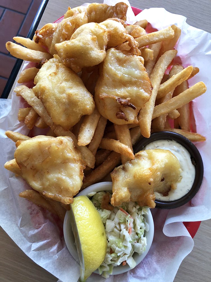 Fish and chips done right—golden batter protecting flaky white cod like delicious armor, with fries standing by as worthy companions in your quest for satisfaction.