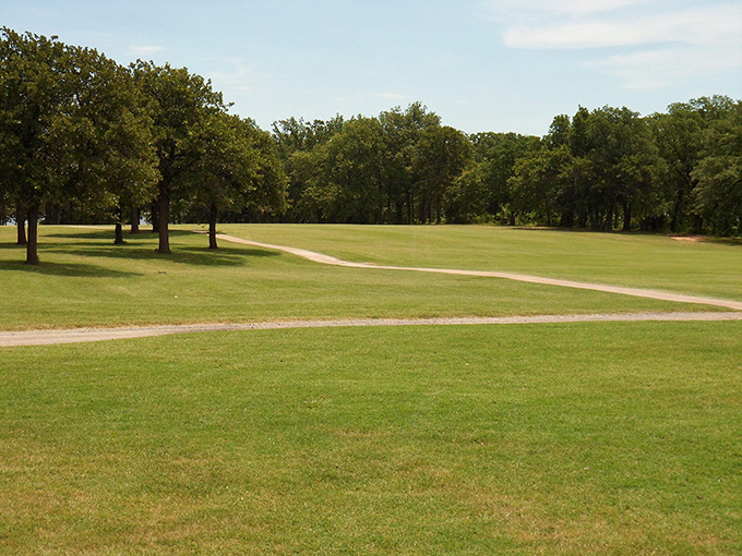 Chandler Golf Course unfurls across the Oklahoma landscape like a green carpet, where ancient oaks frame fairways under endless blue skies.