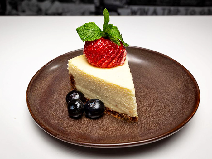 A slice of cheesecake with a precisely fanned strawberry&mdash;because after conquering Mount Sandwich, you deserve a proper victory dessert.