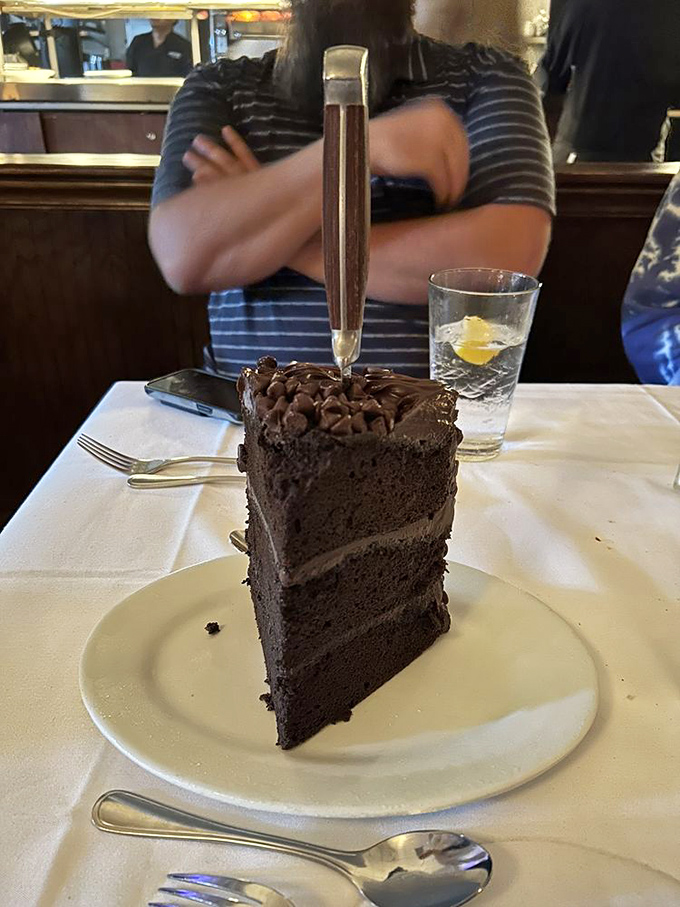 A chocolate cake so tall it needs its own zip code. That knife isn't just for cutting&mdash;it's for scaling this magnificent mountain of cocoa.