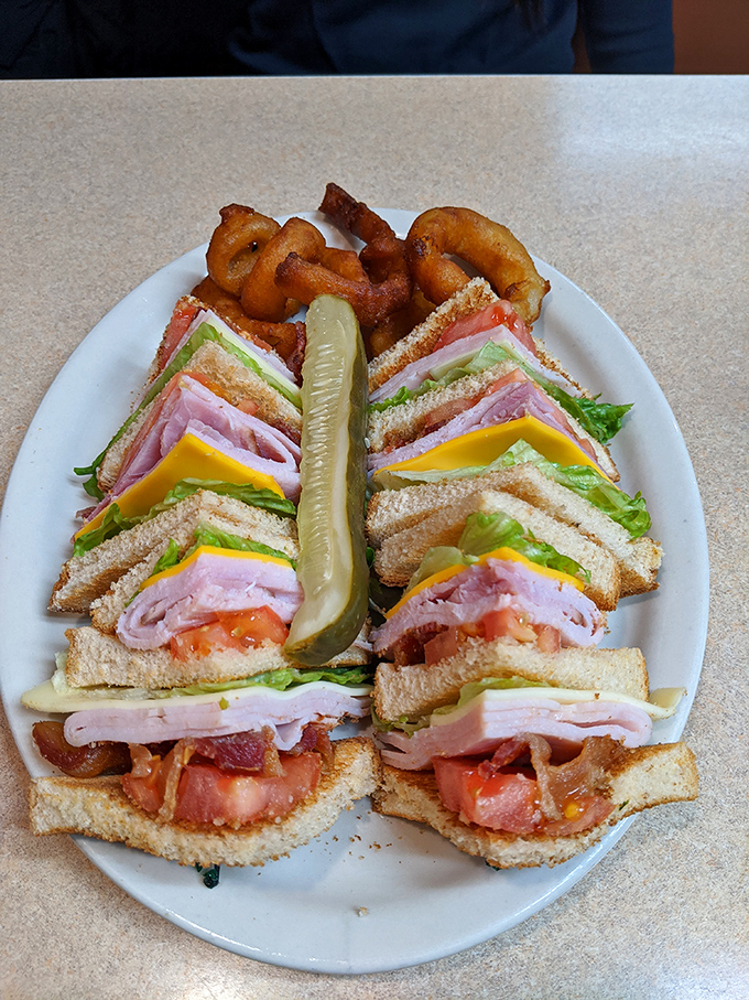 The club sandwich: architectural marvel of the diner world, complete with the ceremonial pickle spear and a handful of onion rings.