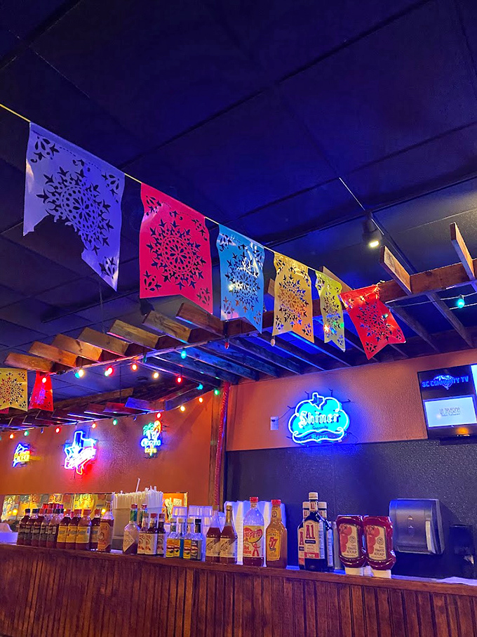 Colorful papel picado banners dance overhead, adding festive flair while neon beer signs remind you this is definitely a place to celebrate.