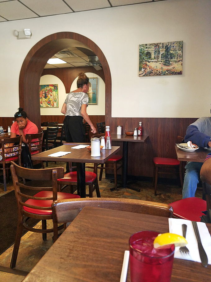 Red chairs and wooden arches frame the daily breakfast ballet. Every regular has their favorite table, and they'll defend it with their lives.