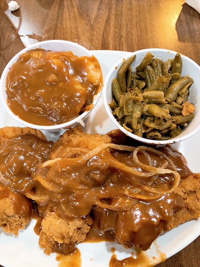 Pork chops swimming in gravy with green beans standing by&mdash;a plate that says "nap time is imminent" in the most delicious way.