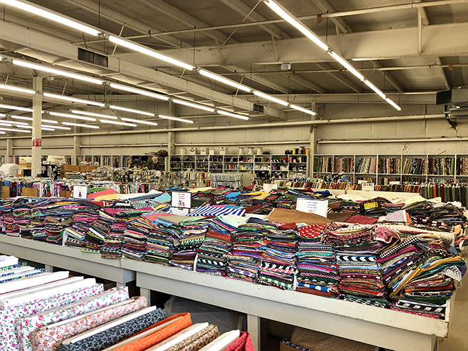 Tables piled high with fabric remnants&mdash;a treasure hunter's paradise where your next "happy accident" project is hiding in plain sight.