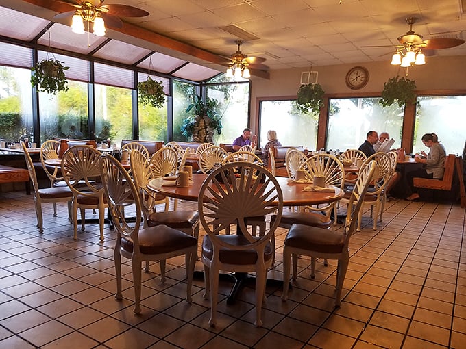 Sunlight streams through windows into this breakfast sanctuary where fan-backed chairs await the faithful morning crowd.