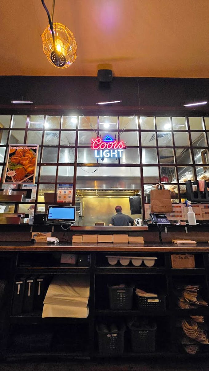 Behind the scenes where burger dreams materialize—the kitchen window offering glimpses into the controlled chaos of creation.