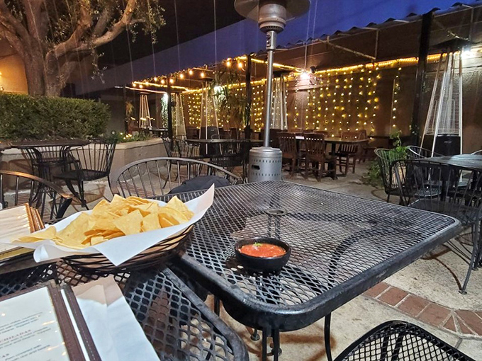 Evening transforms the patio into a twinkling oasis. String lights cast a gentle glow over tables where chips and salsa are just the beginning of the story.