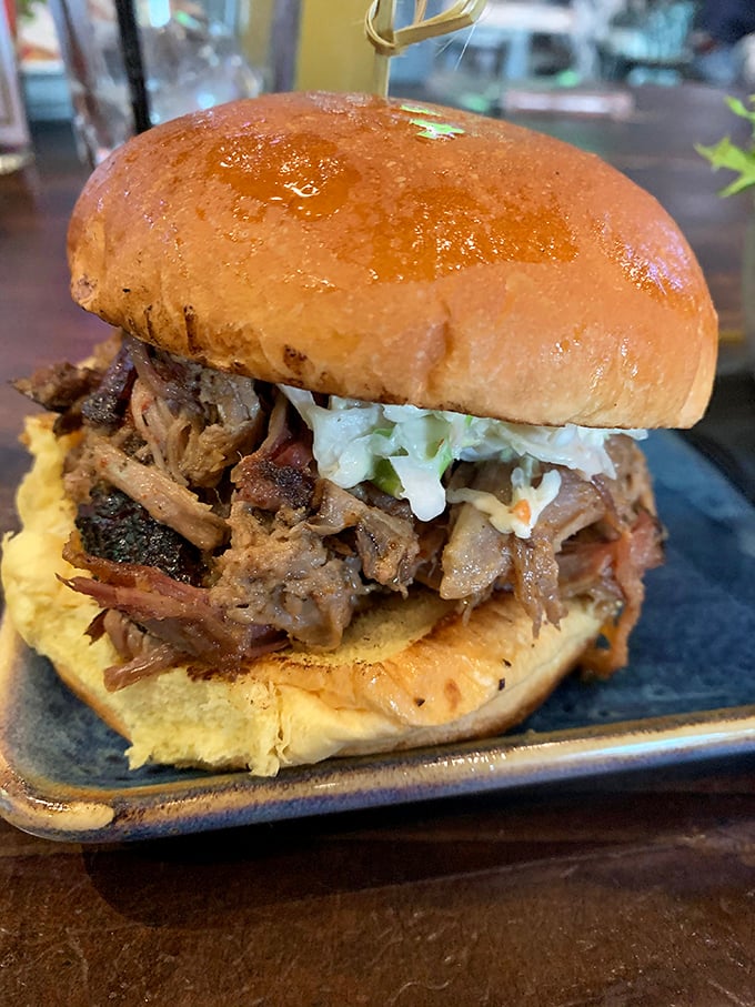 A pulled pork sandwich that requires both hands and several napkins&mdash;the universal sign of barbecue excellence. That golden bun is just trying to contain the glory.