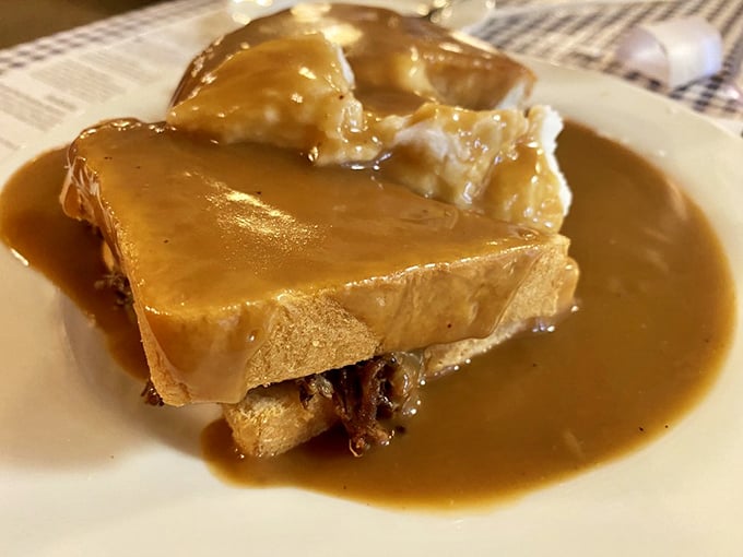 Hot roast beef sandwich swimming in gravy &ndash; comfort food that wraps around your soul like a handmade quilt.