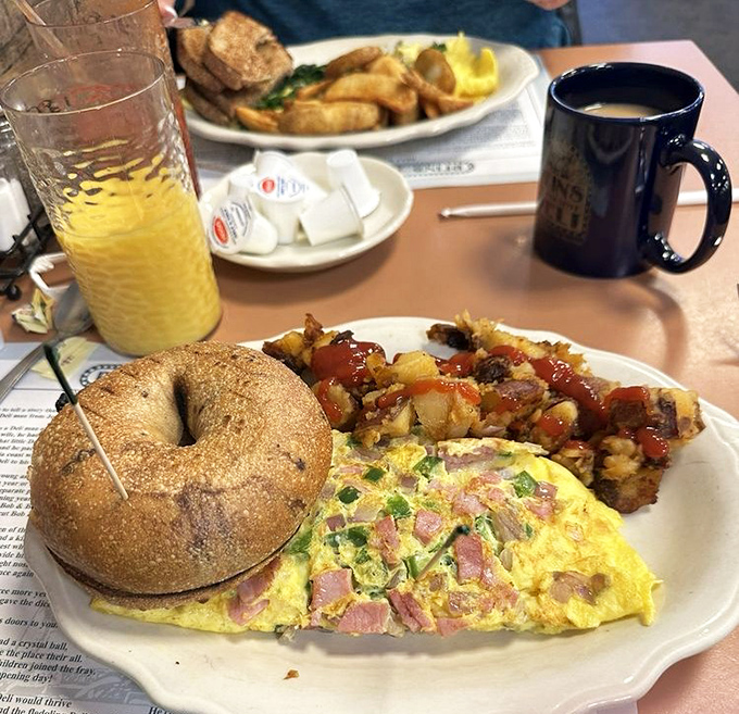 A ham and cheese omelette lounges on its plate alongside potatoes and a bagel—the breakfast equivalent of a three-piece band that knows all the classics.